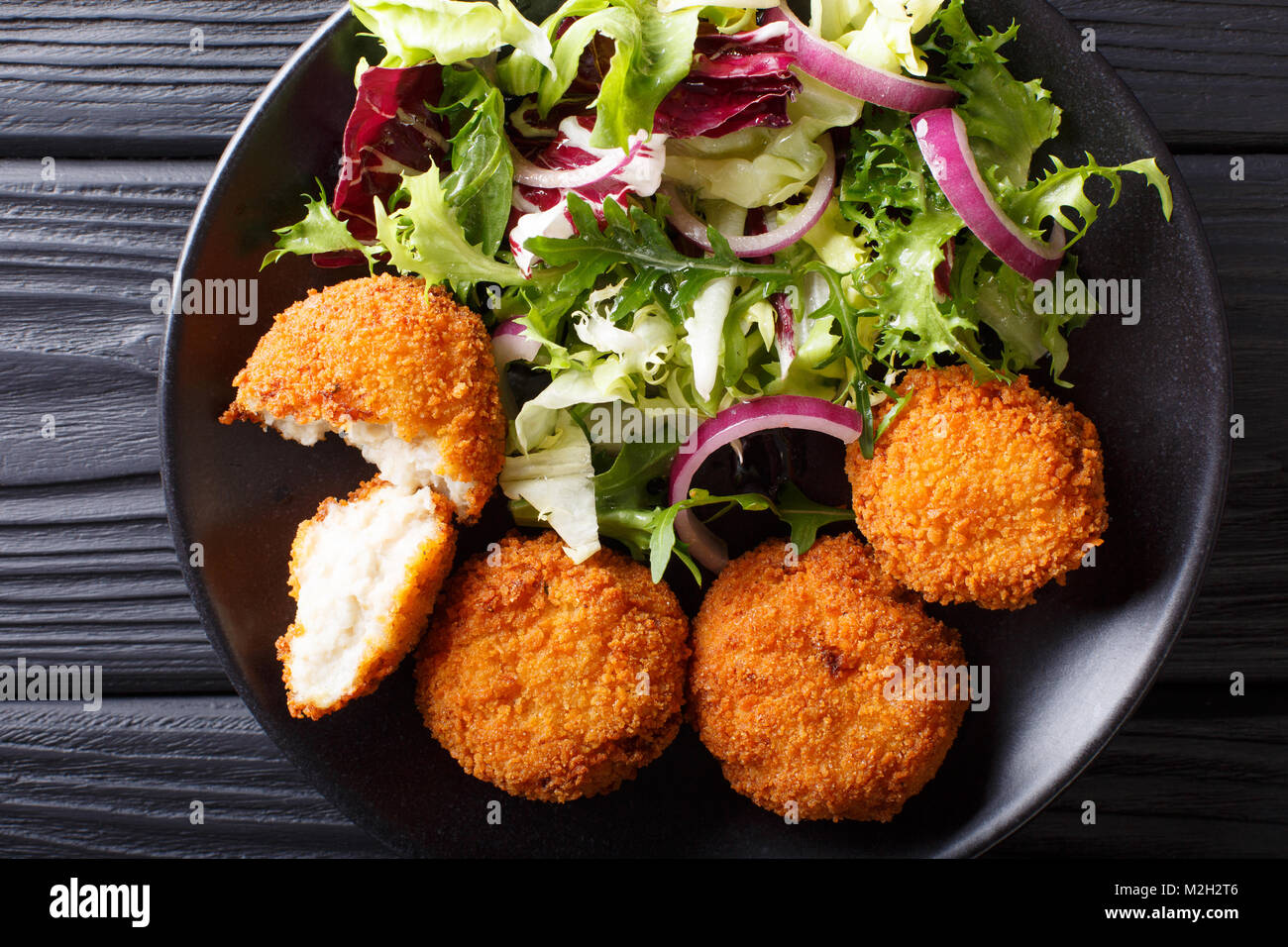 Cod cake in breading with fresh mix salad close-up on a plate ...