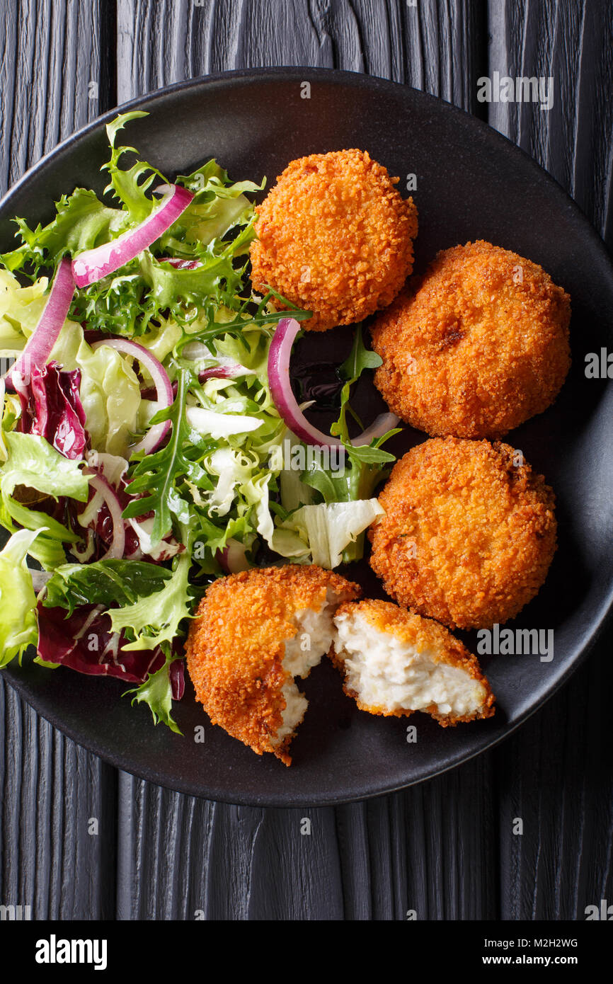 Cod cake in breading with fresh mix salad close-up on a plate. Vertical ...