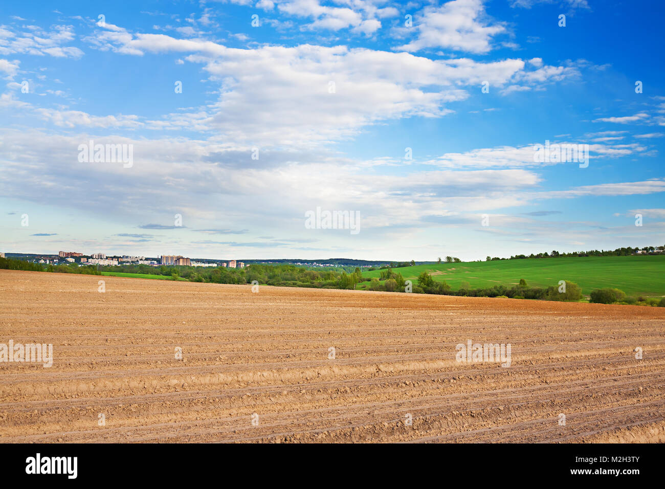 spring of landscape with ploughed field and blue sky with white clouds ...