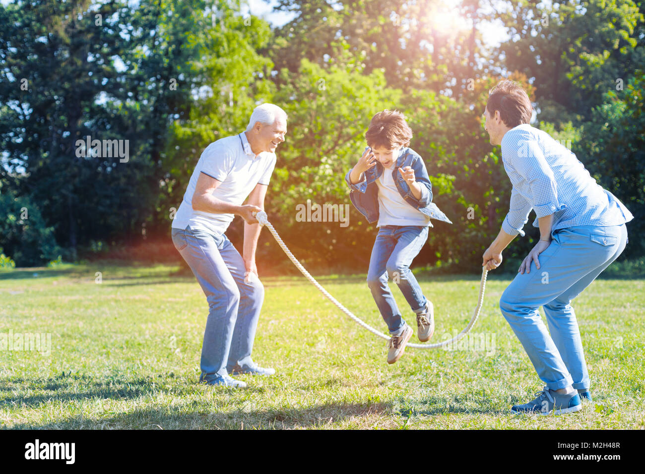 Supportive family playing with jump rope in park Stock Photo - Alamy