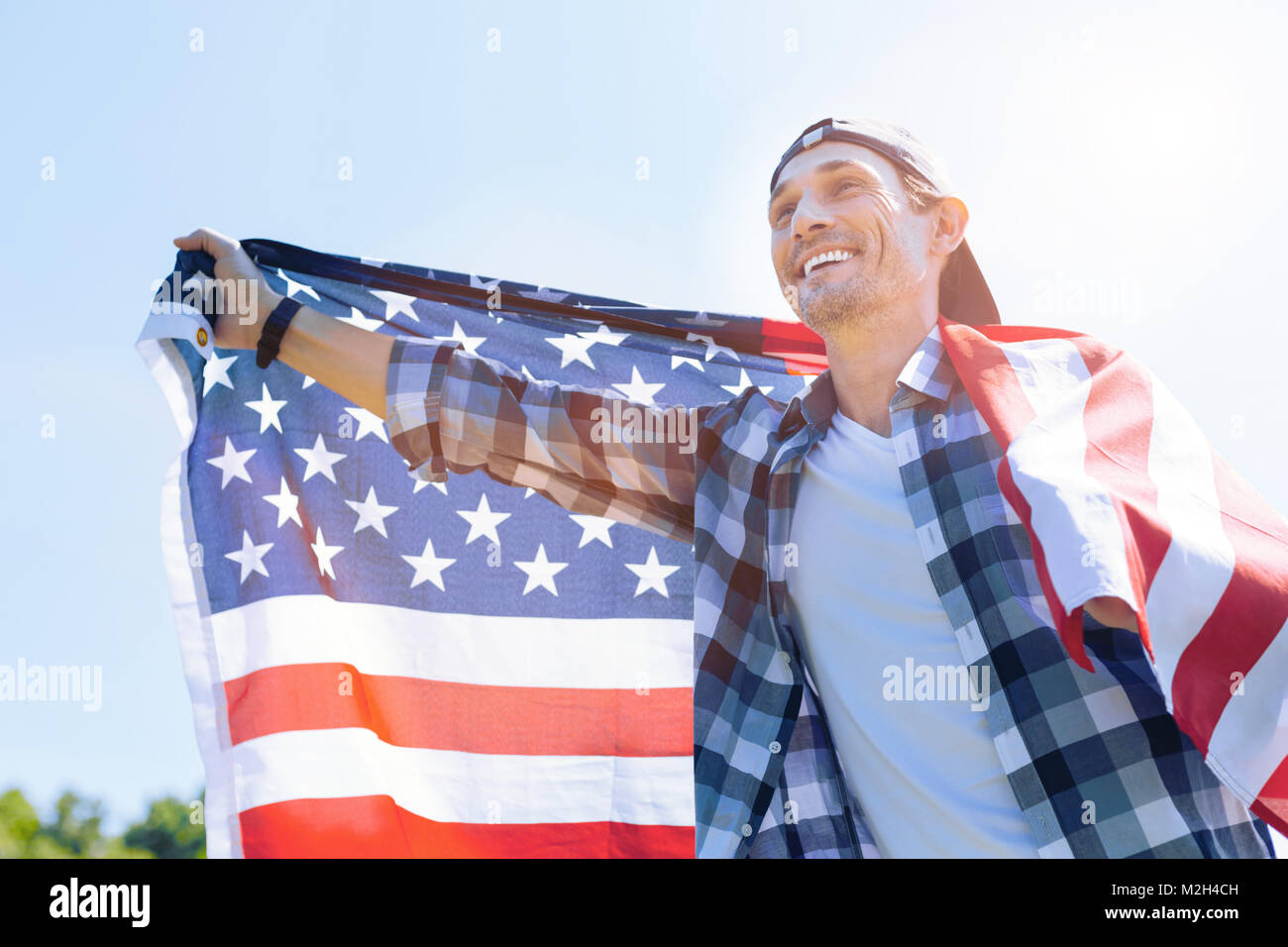 True patriot smiling cheerfully while holding american flag Stock Photo ...