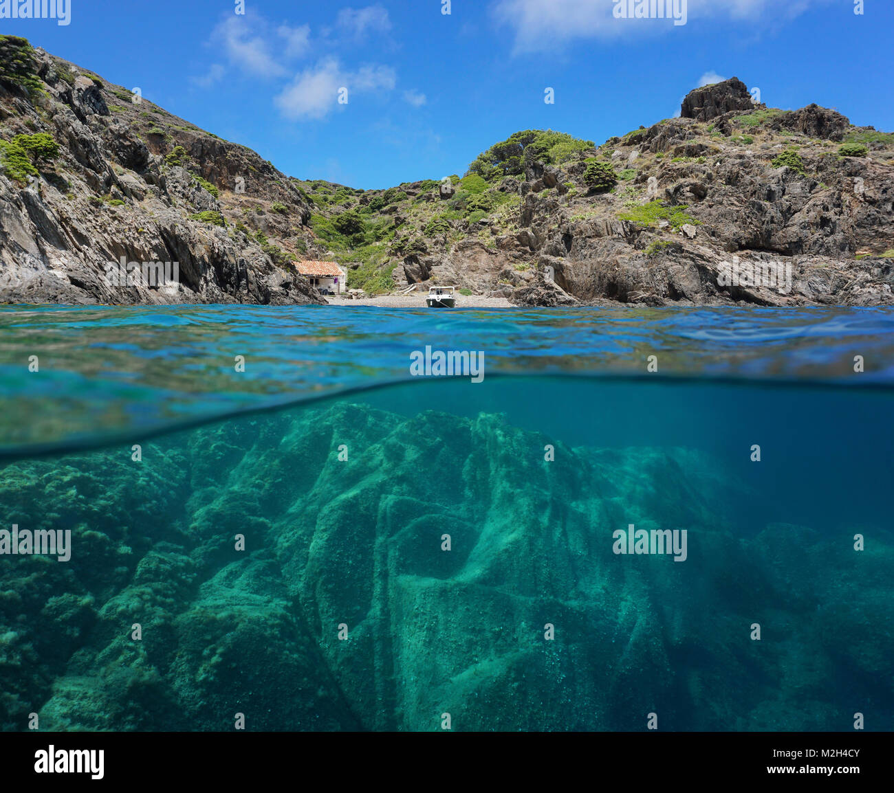 Rocky coastline with a cove and rock underwater, split view above and ...