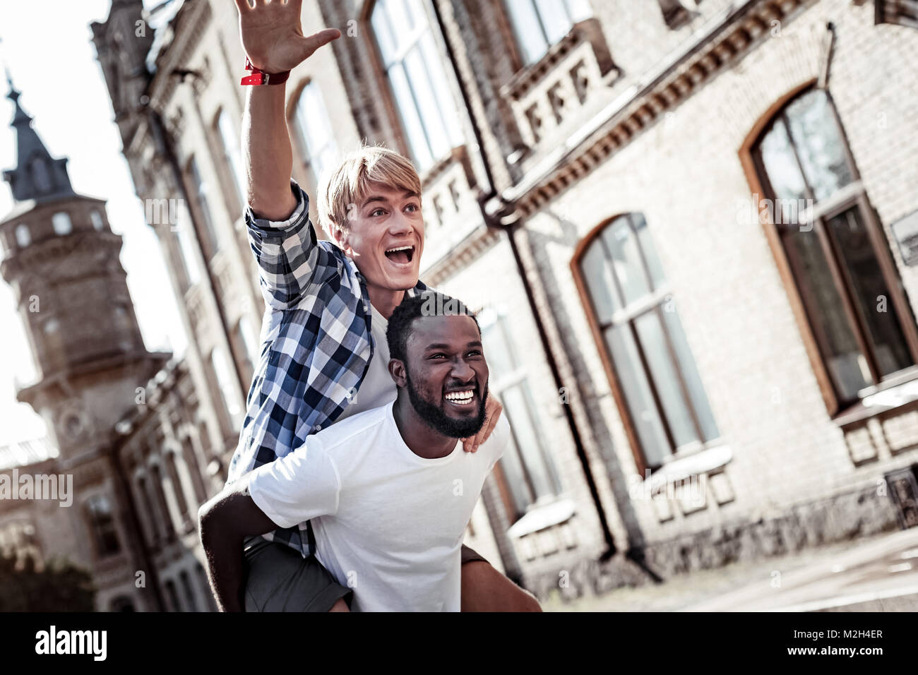 Delighted strong man carrying his friend Stock Photo - Alamy