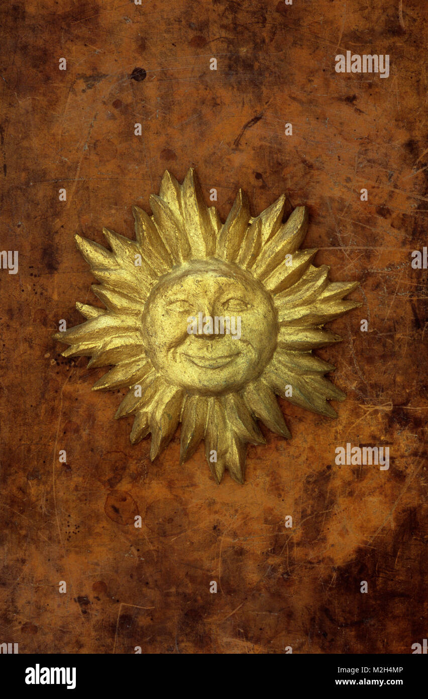 Plaster vintage model of smiling sun painted gold and set against ...