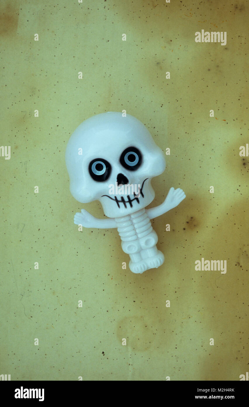 Plastic comical caricature of smiling large skull on tiny body skeleton ...