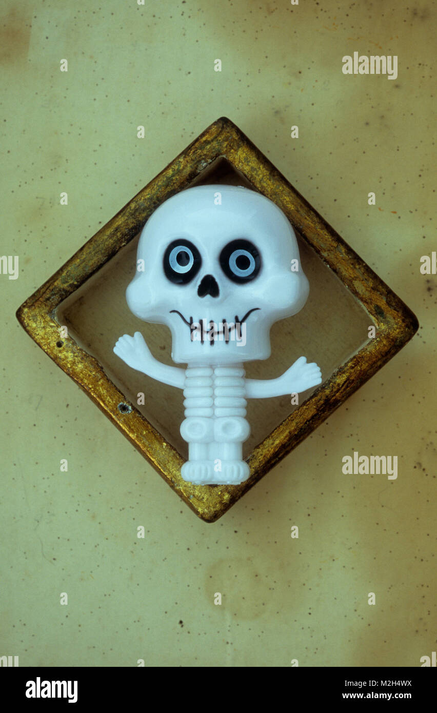 Plastic comical caricature of smiling large skull on tiny body skeleton ...