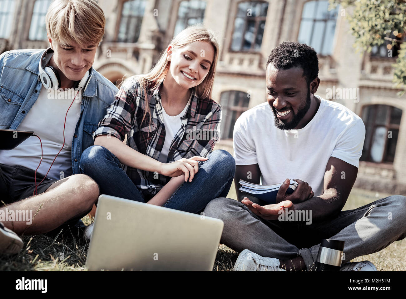 Delighted happy students sitting on the grass Stock Photo - Alamy