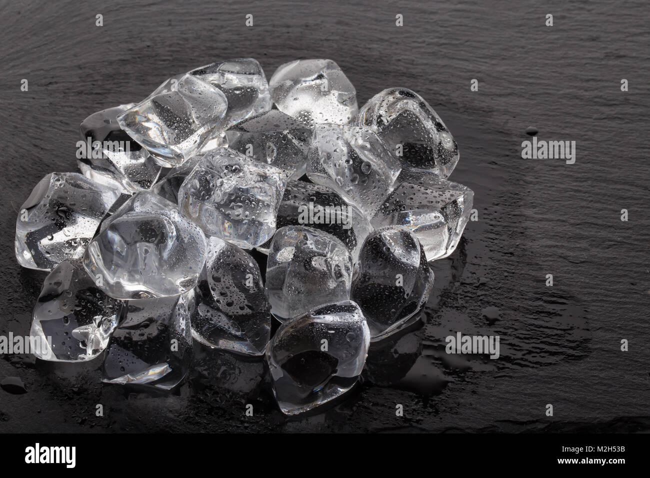 A pile of ice cubes on black slate board with drops of water Stock ...