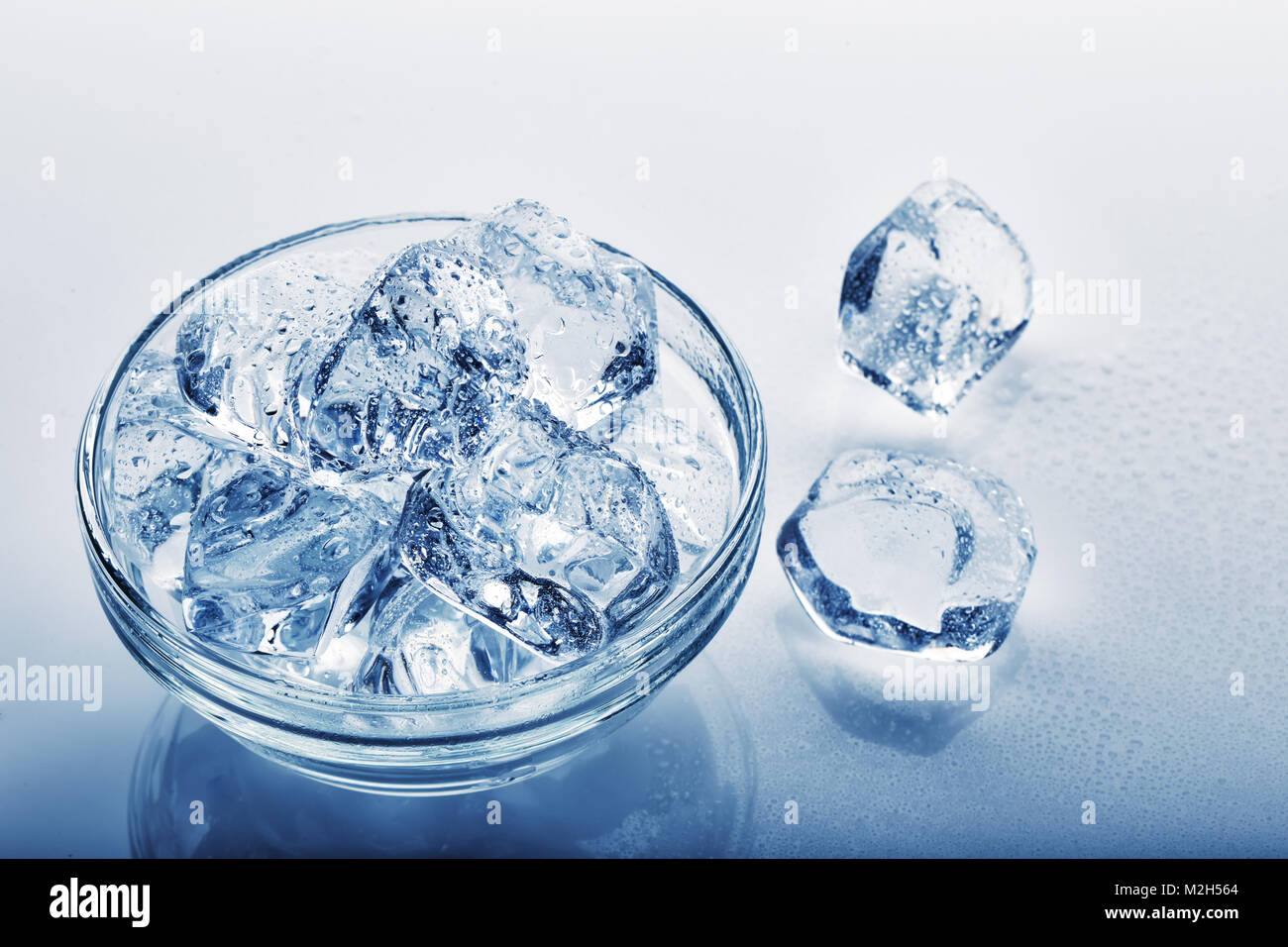 Frozen ice cubes in glass plate on wet table Stock Photo - Alamy