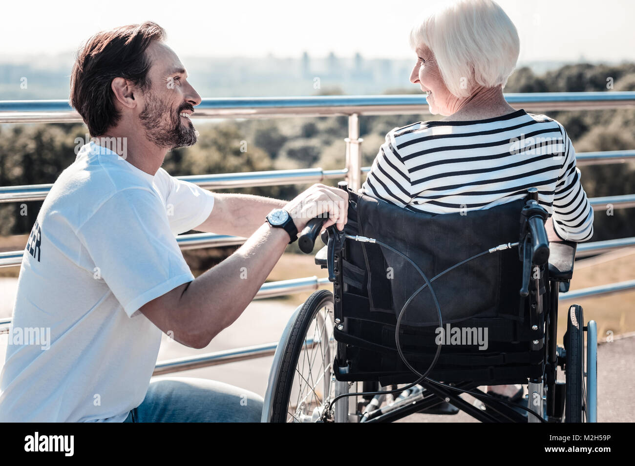 Positive nice man helping a disabled woman Stock Photo - Alamy