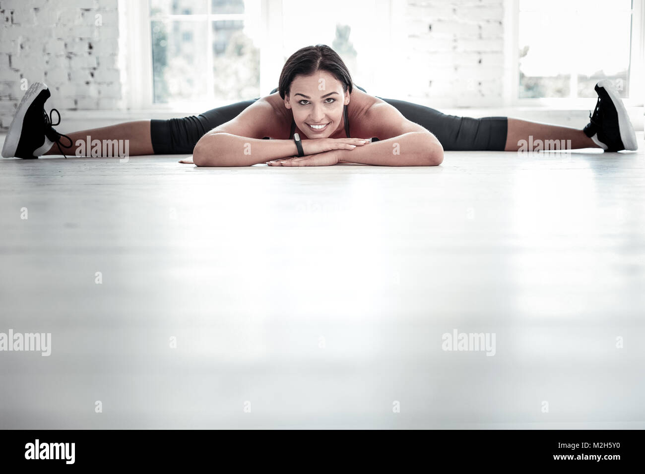 Cheerful young woman doing splits at gym Stock Photo - Alamy