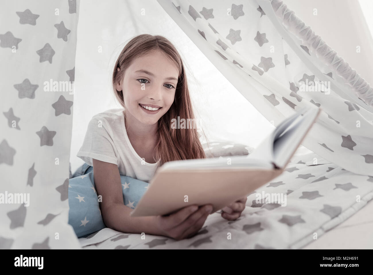 Cute smiling girl reading a book Stock Photo - Alamy