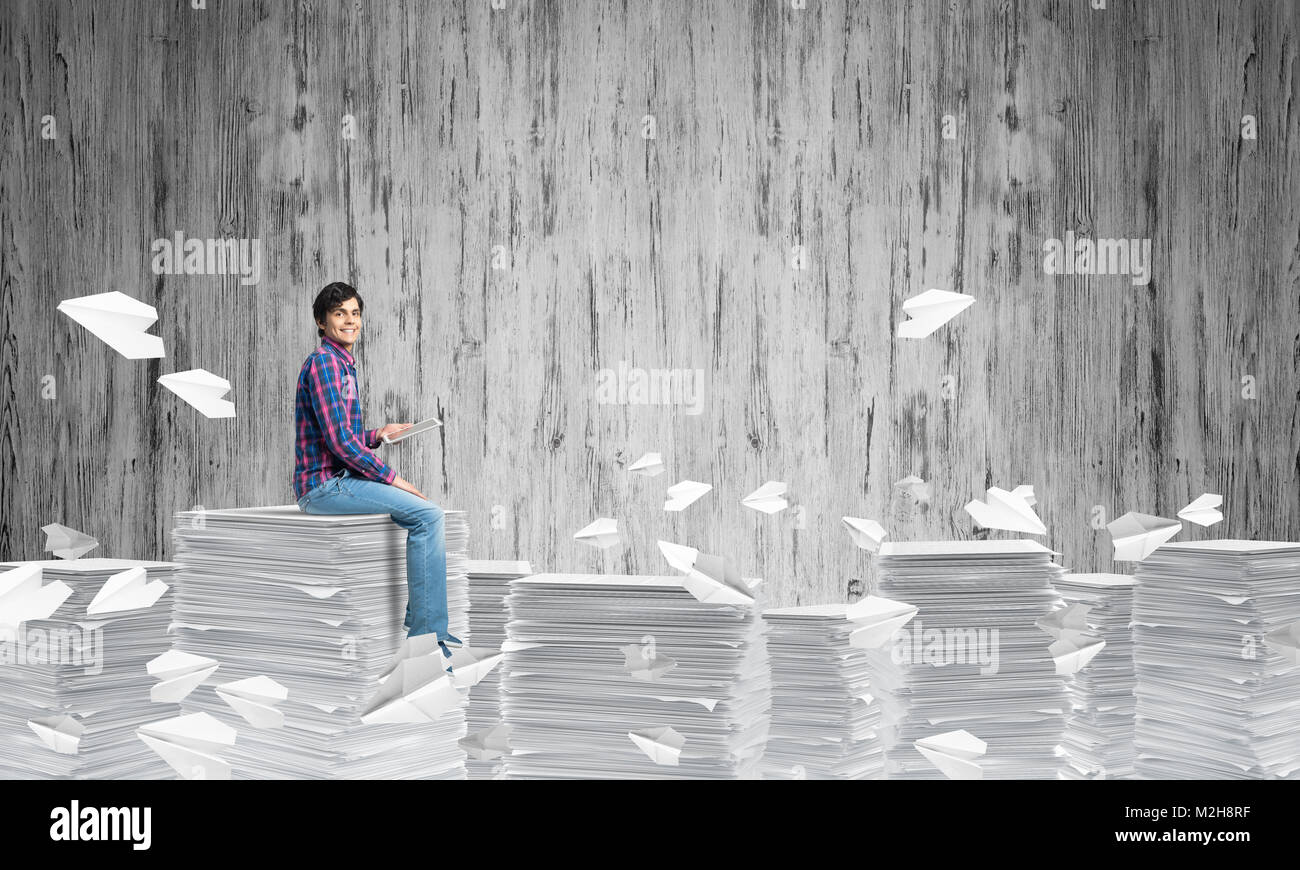 Attractive man sitting on pile of paper documents Stock Photo - Alamy
