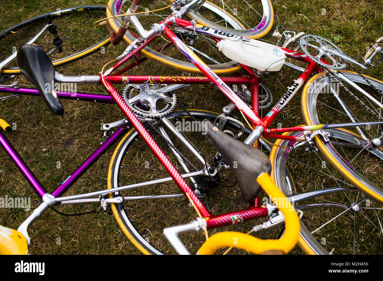 A cluster of racing and fixed-gear bicycles are left in the grass ...