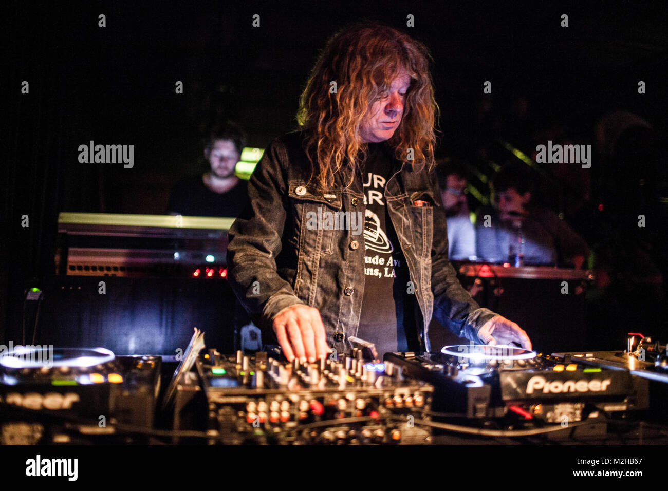 A longhaired nerdy-looking dj wears a denim jacket and makes sure there ...