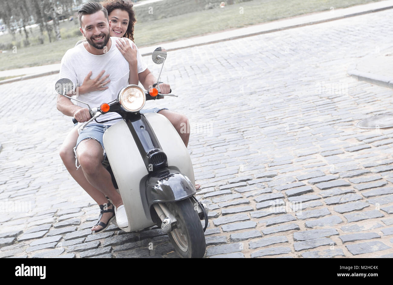 Young couple riding motor scooter in city Stock Photo - Alamy