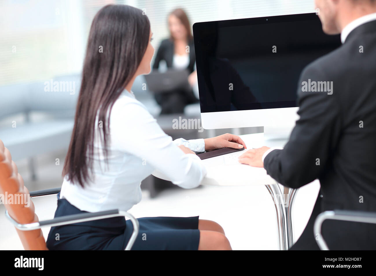 rear view.two successful employee sitting behind a Desk Stock Photo - Alamy