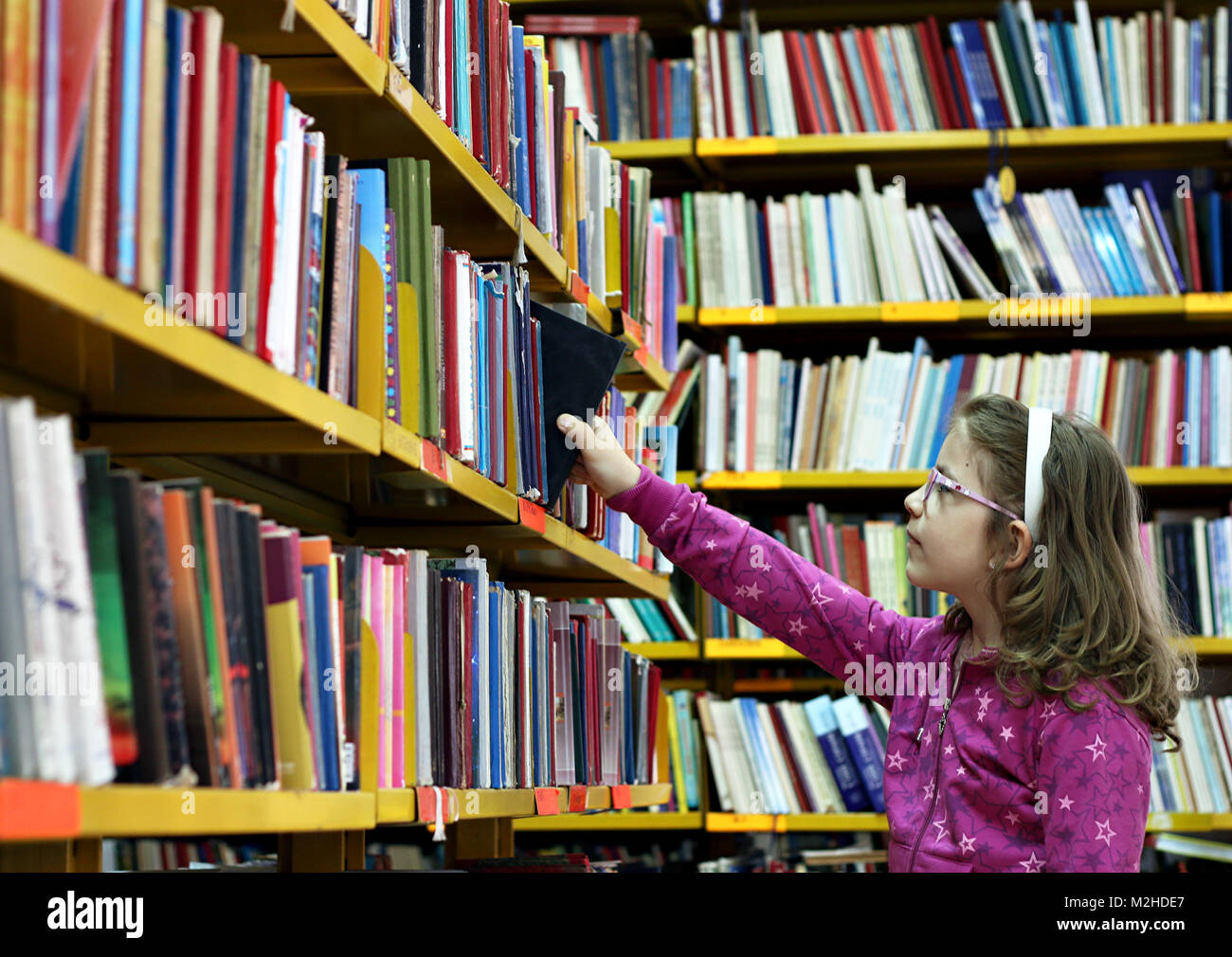 little girl takes a book at the library Stock Photo - Alamy
