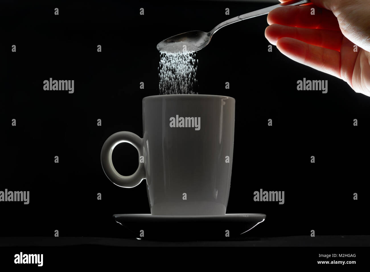 Tea cup and pouring sugar spoon on black background Stock Photo - Alamy