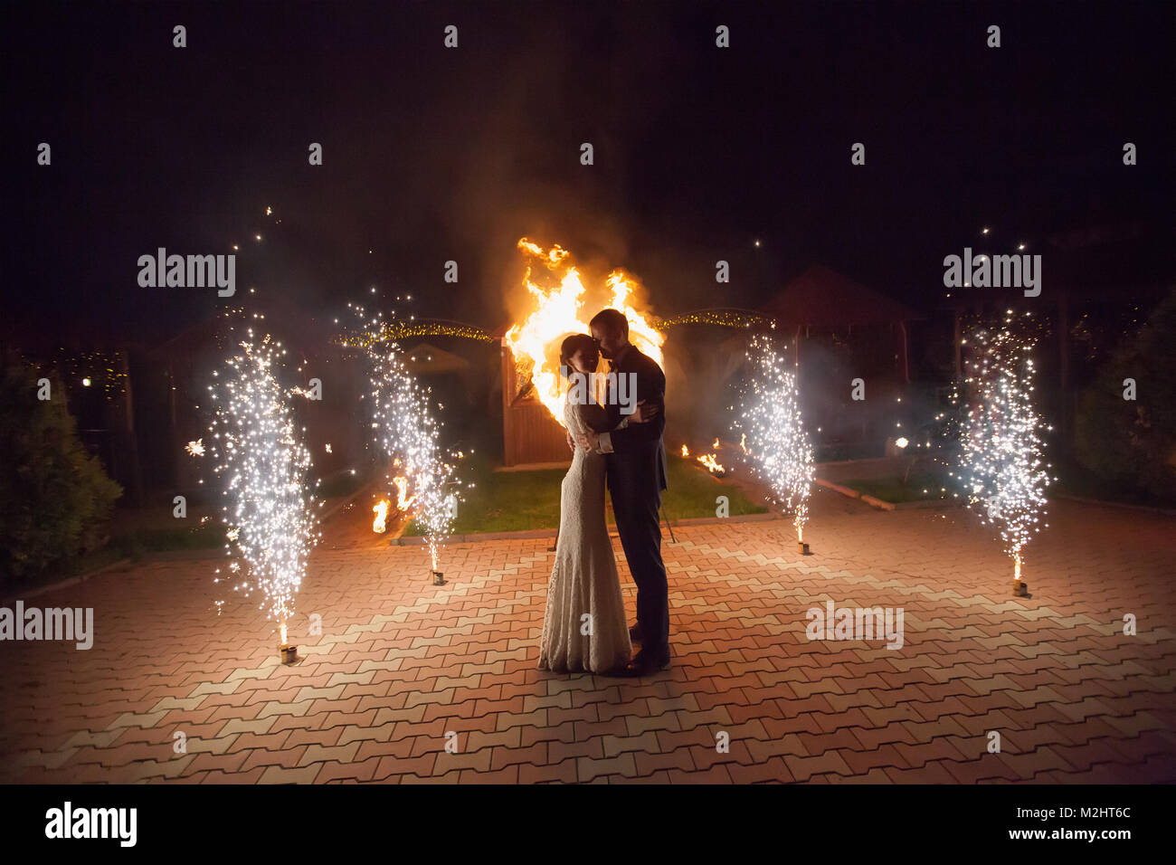 Young groom and bride with two burning hearts fireshow at night ...