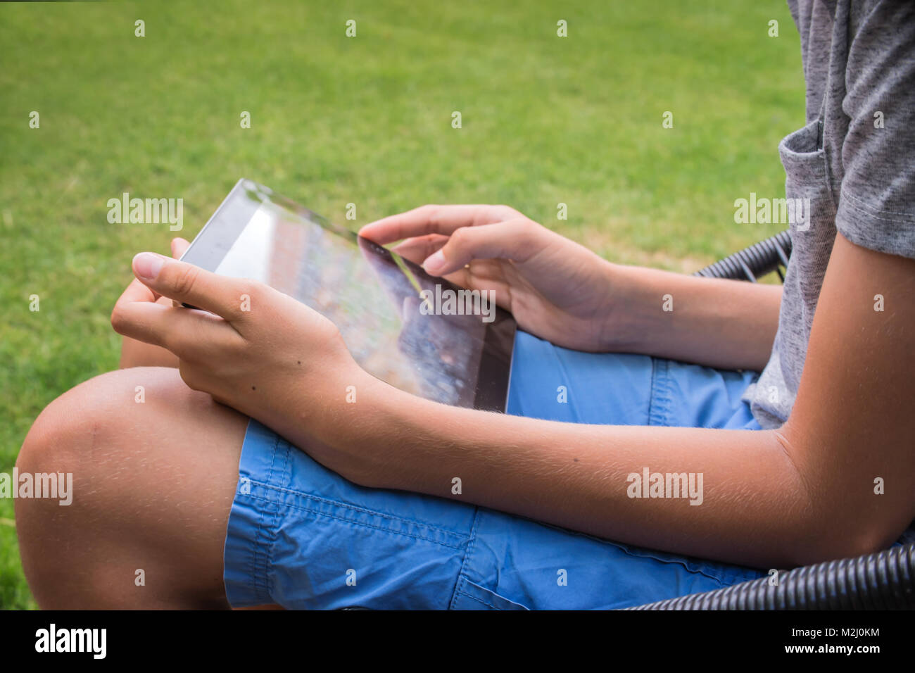 Boy with a tablet outdoor, green lawn background Stock Photo - Alamy