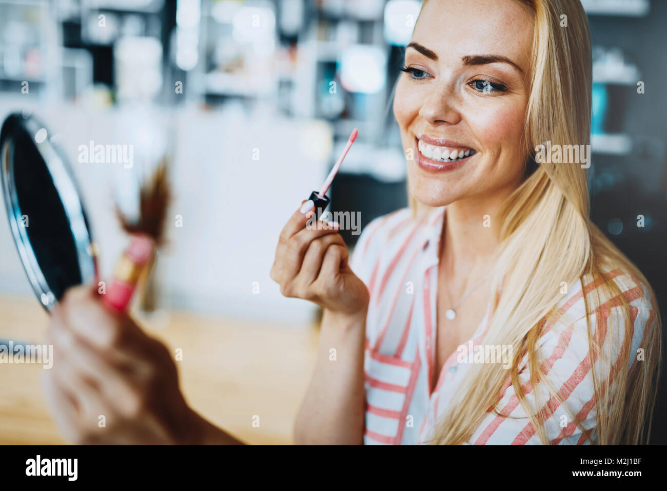 Young beautiful woman applying make up using small mirror Stock Photo ...