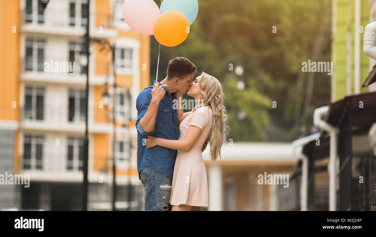 Girlfriend and boyfriend with balloons kissing in street, romantic ...