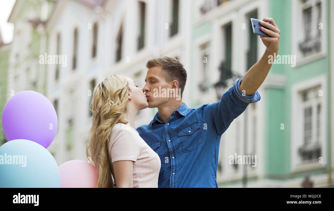 Sweethearts kissing in front of smartphone camera taking romantic ...