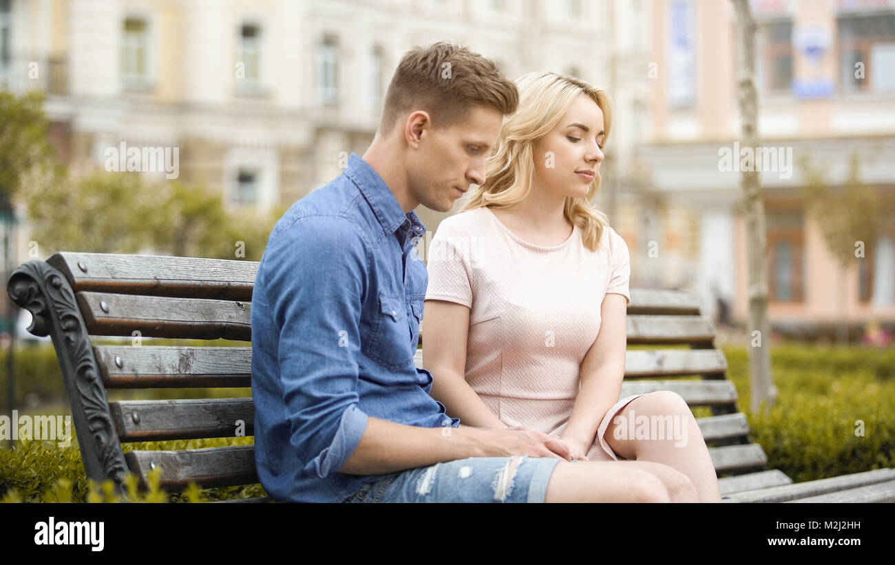 Couple feeling awkward, sitting on bench in silence, crisis in ...