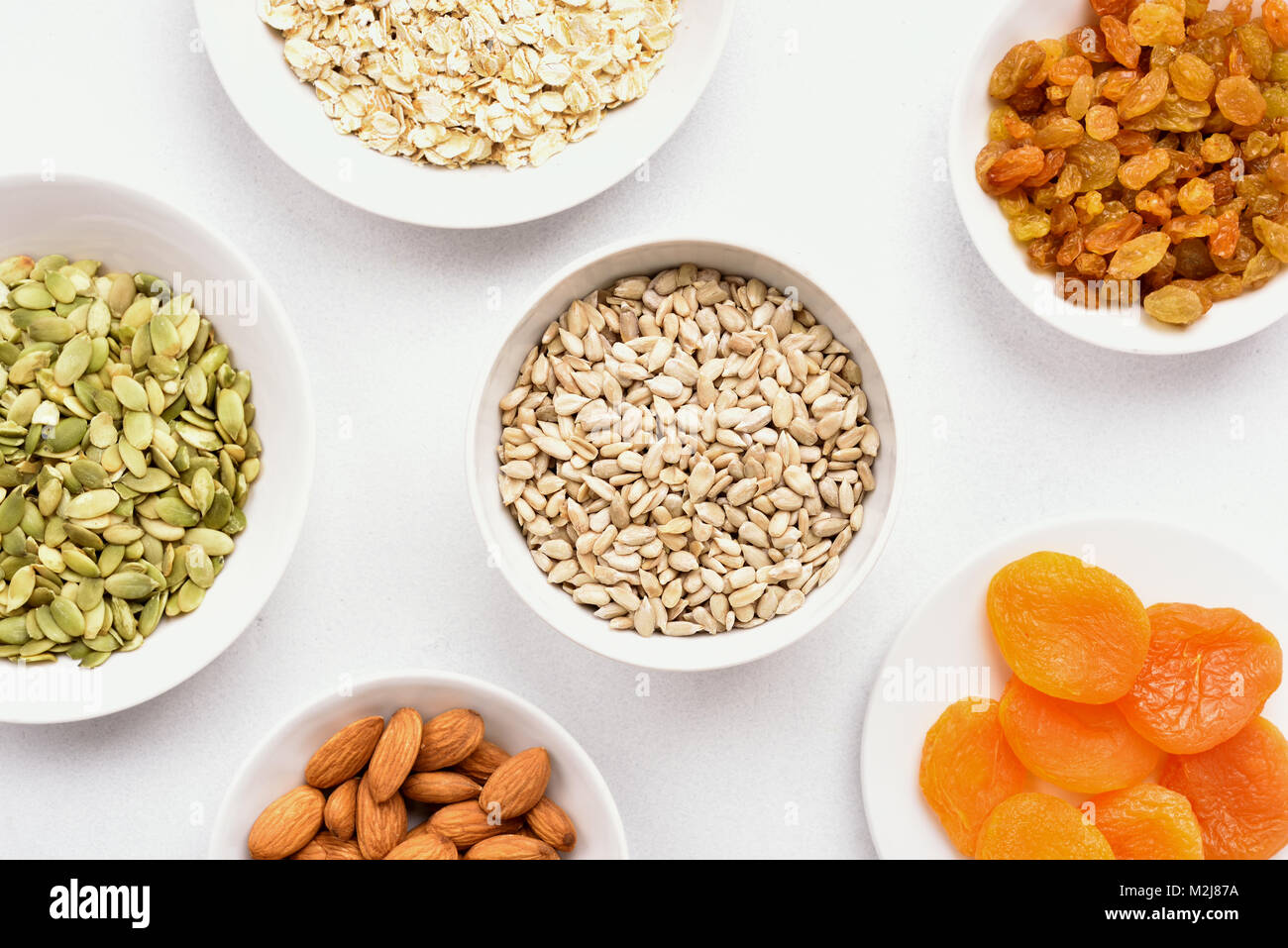 Bowl with ingredients for cooking granola on white background. Healthy ...