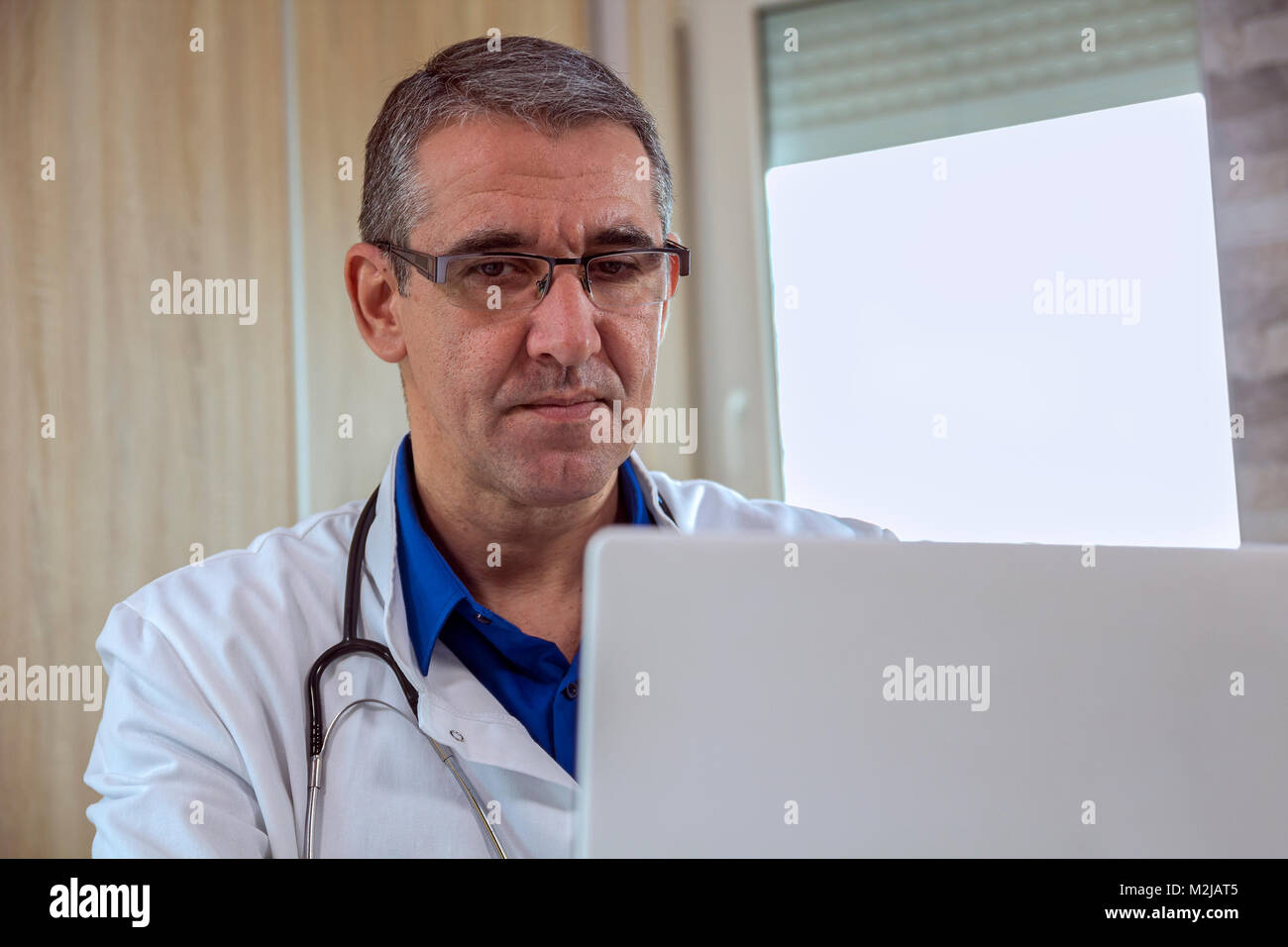 The doctor in a white coat with a stethoscope around his neck, typing ...