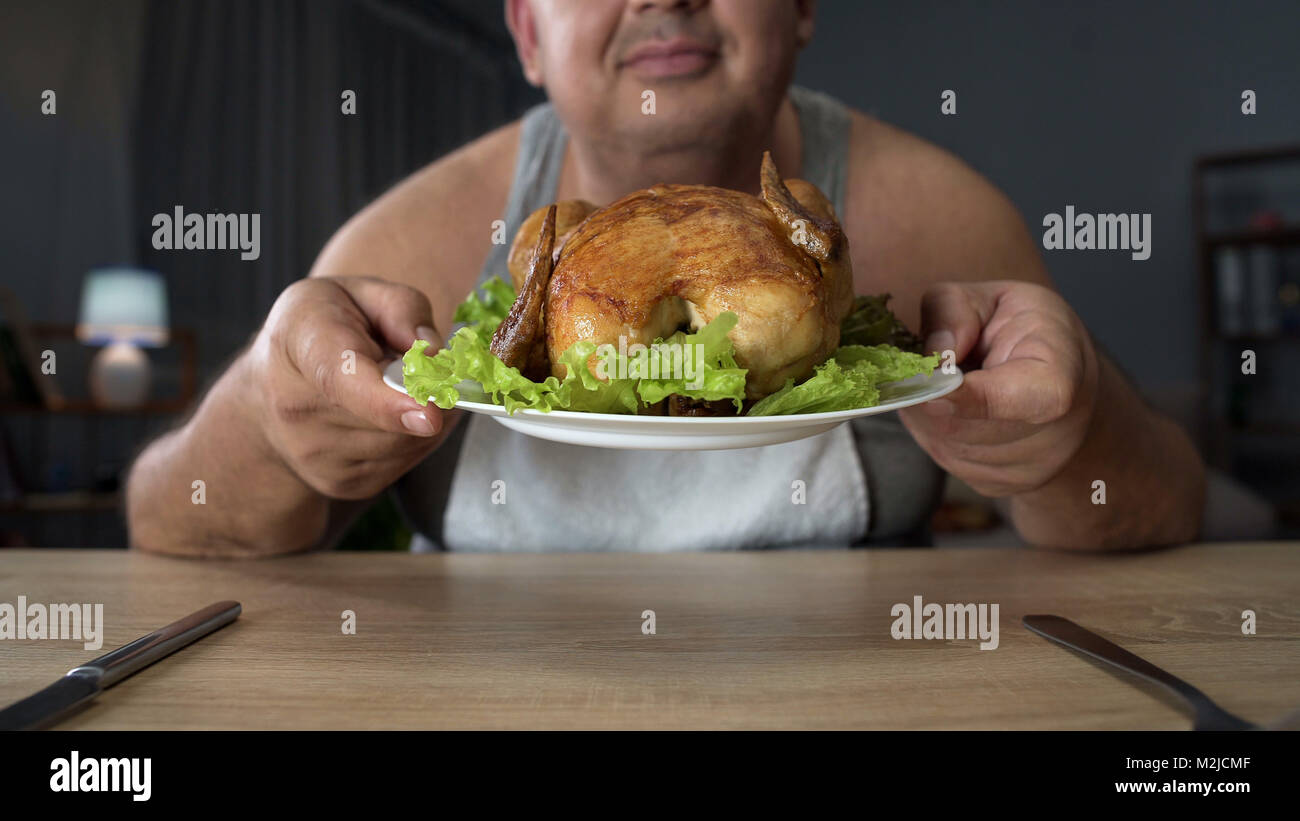 Overweight man smelling greasy grilled chicken with enjoyment ...