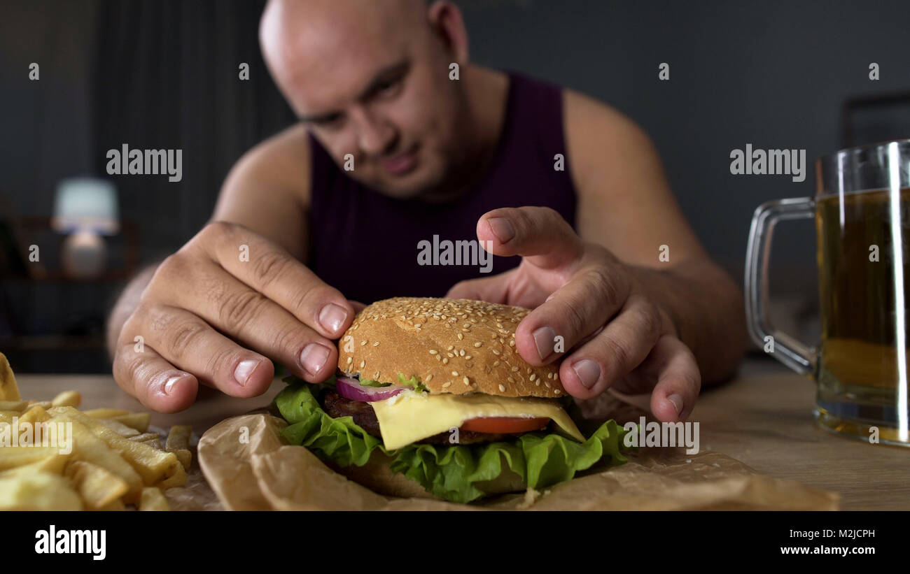 Obese man cooking big burger, overeating gourmet admiring his meal ...