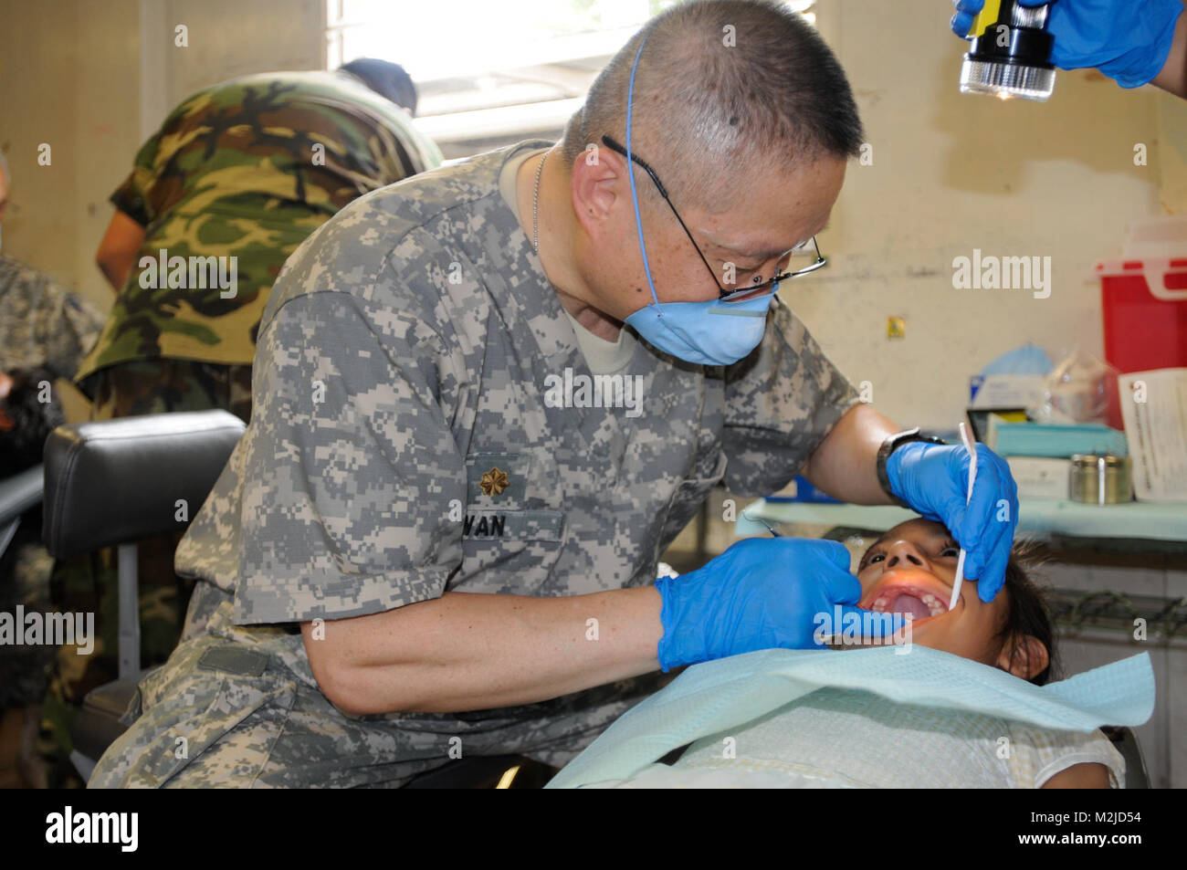 Maj. George Wan from Los Angeles examines a child's teeth in El ...