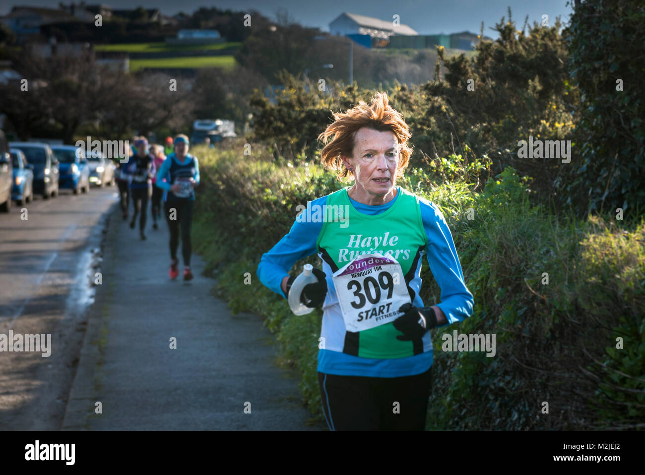 A mature female runner competing in a road race in Newquay Cornwall ...