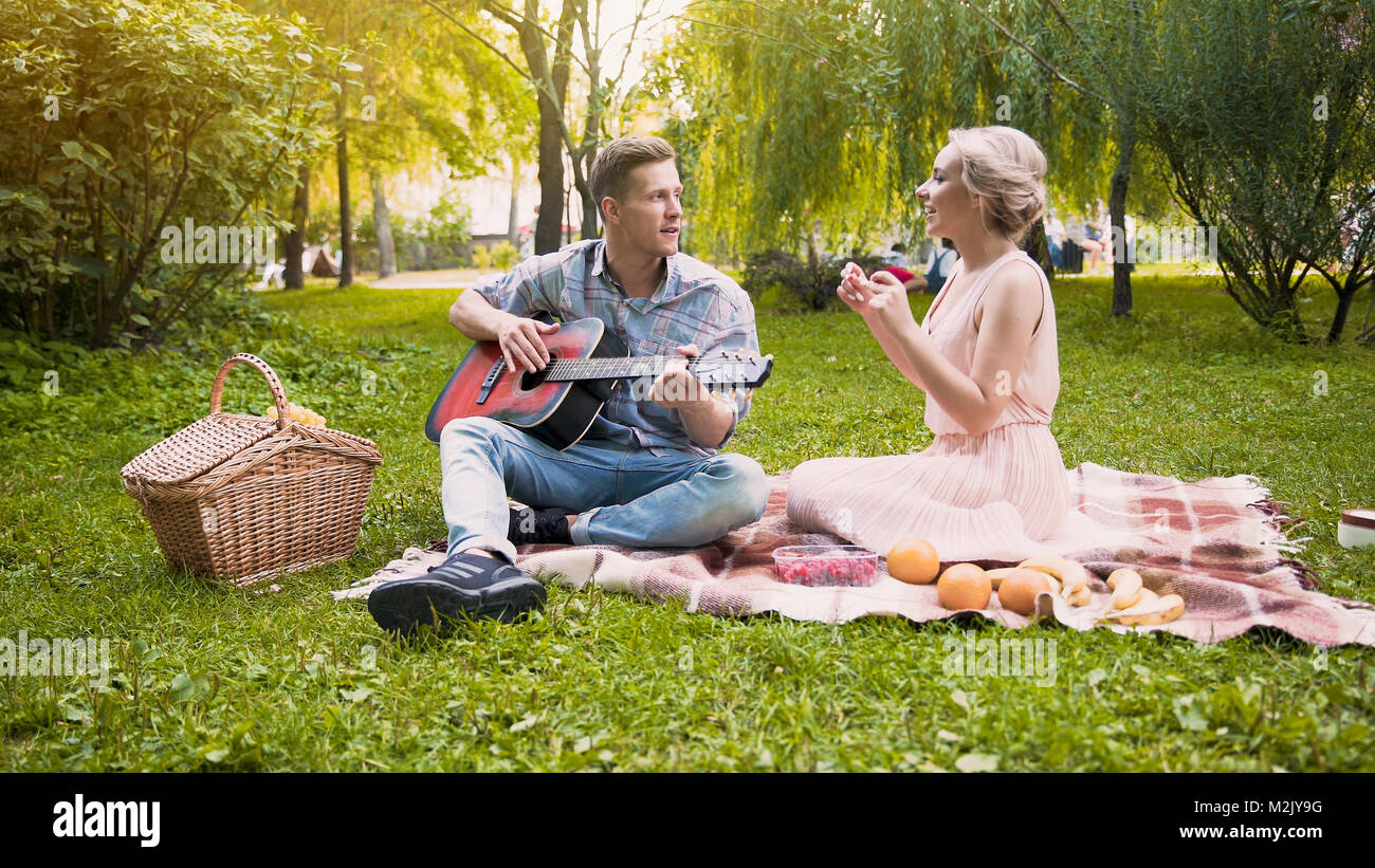 Couple having romantic date, singing songs and playing guitar, sitting ...