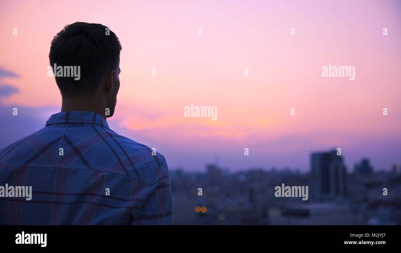 Young man standing on roof of building alone and meditating, enjoying ...