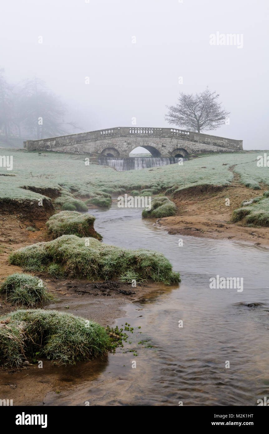 Hovingham Beck flowing under an ornate stone bridge and cascading over ...