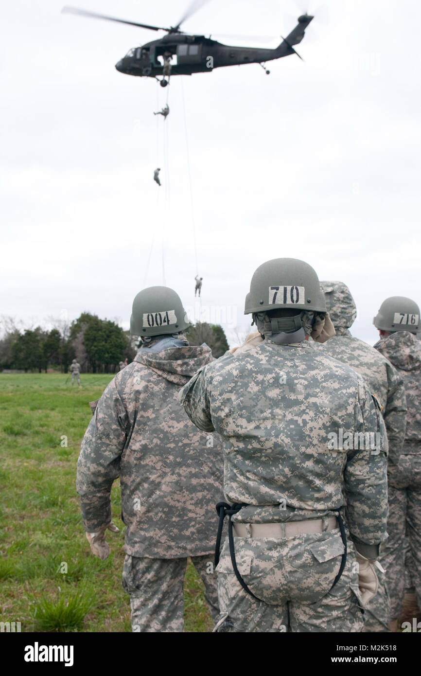 Soldiers watch as classmates rappel from a UH-60 Black Hawk helicopter ...