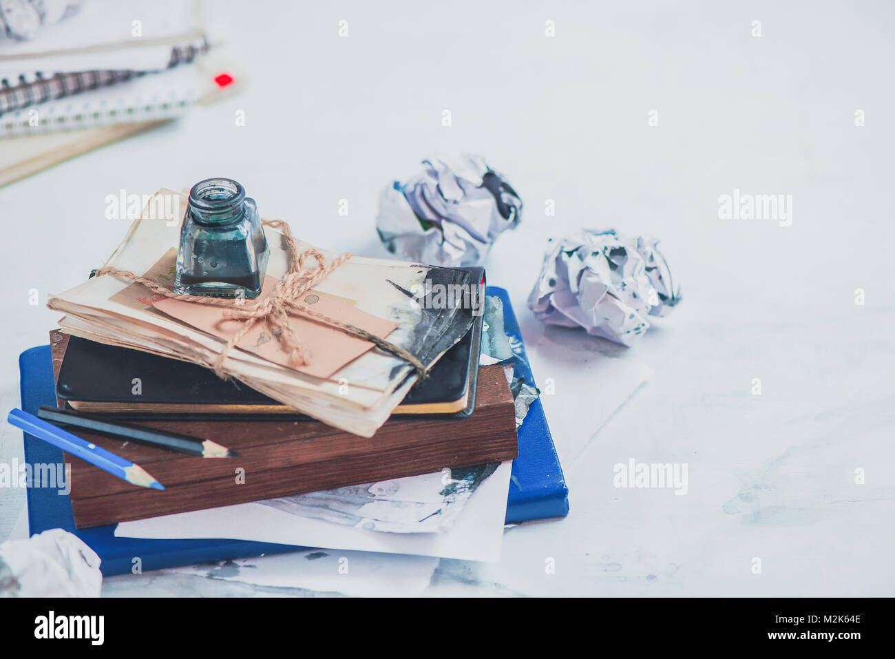 Inkwell on a stack of drafts, pencil boxes and papers.High key still ...