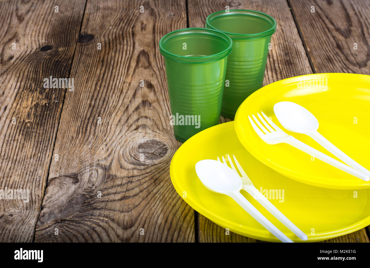 Plastic disposable tableware on wooden table Stock Photo - Alamy