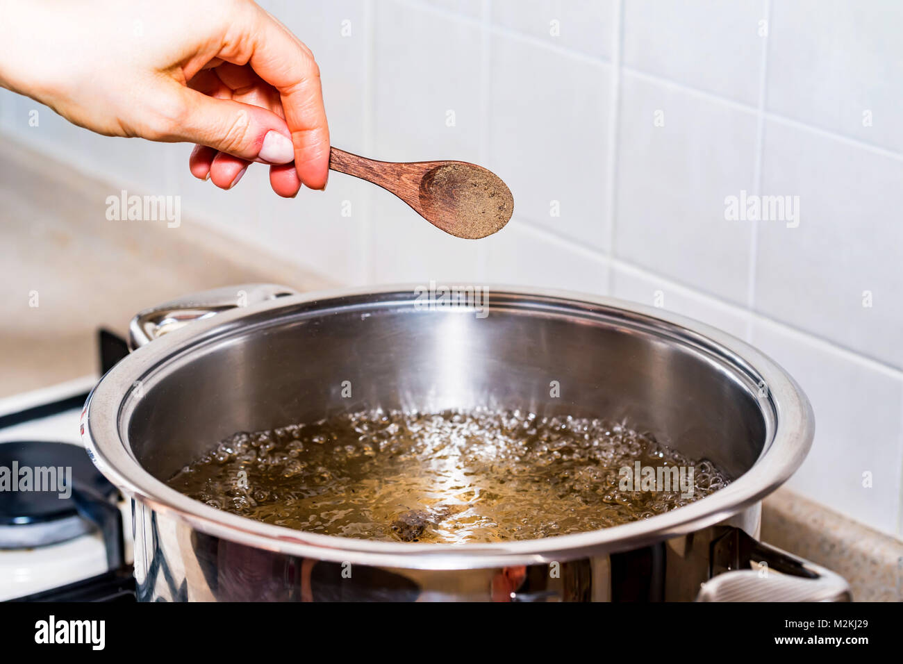 Adding pepper in boiling water, cooking soup Stock Photo - Alamy