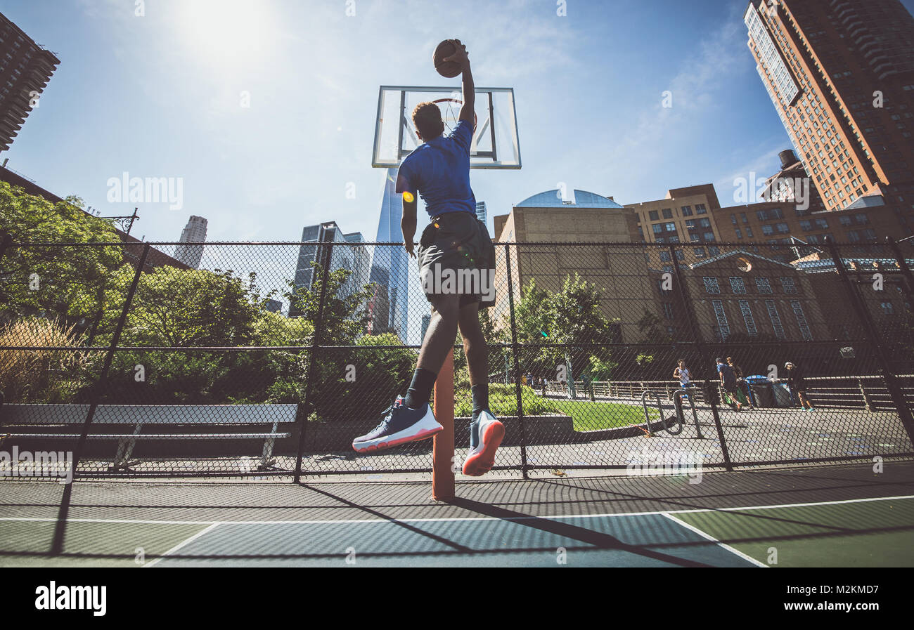Street basketball athlete performing huge slam dunk on the court, New ...