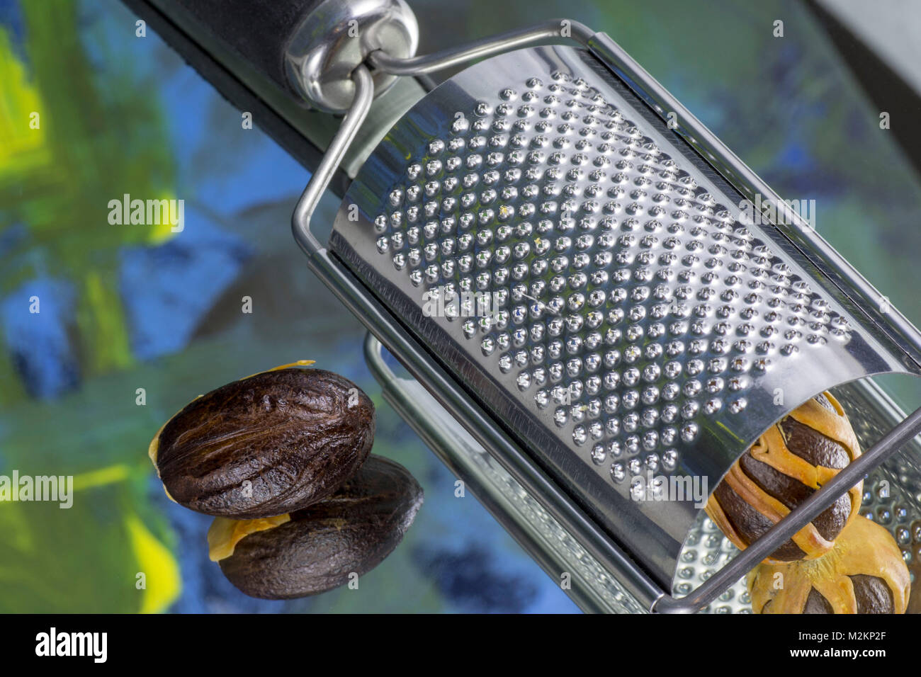 Nutmeg, Mace covering and grater on a reflective background food still ...