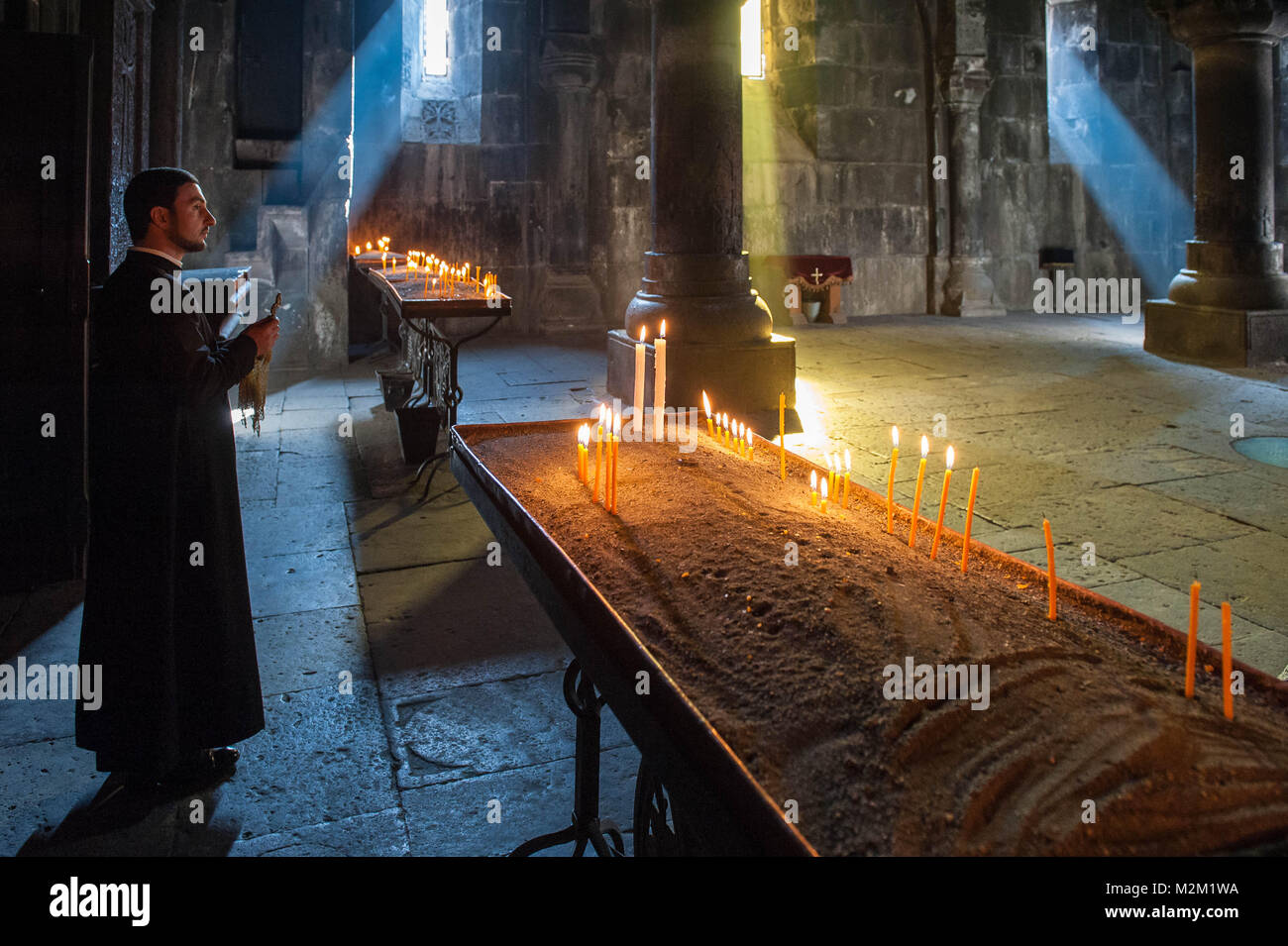 Monk waiting by candlelight in the main church hall of the monastery of ...