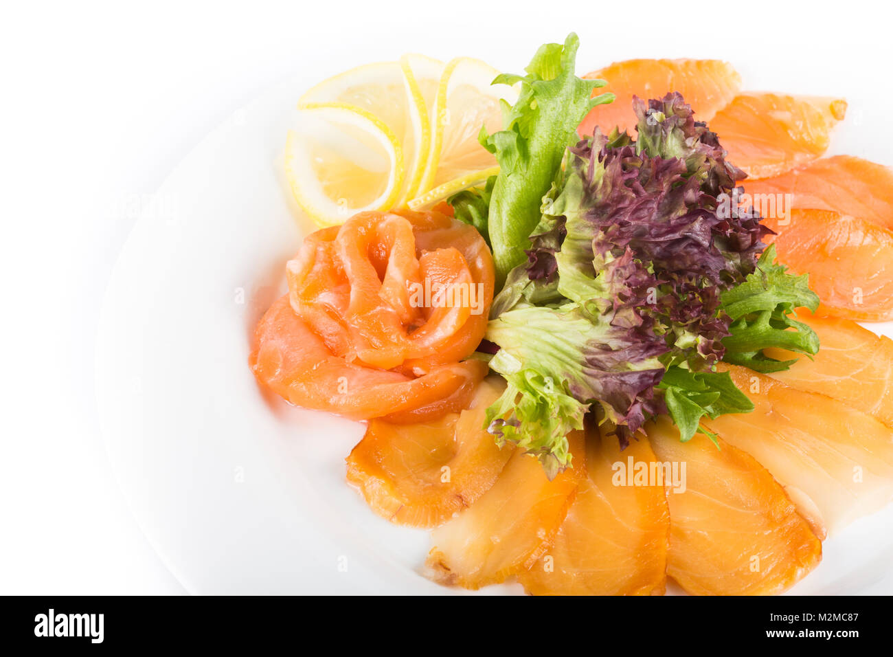 Assorted fish on a plate with lettuce and lemon on a white background ...