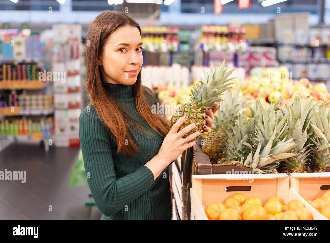 Young brunette woman buying pineapple at grocery shop Stock Photo - Alamy