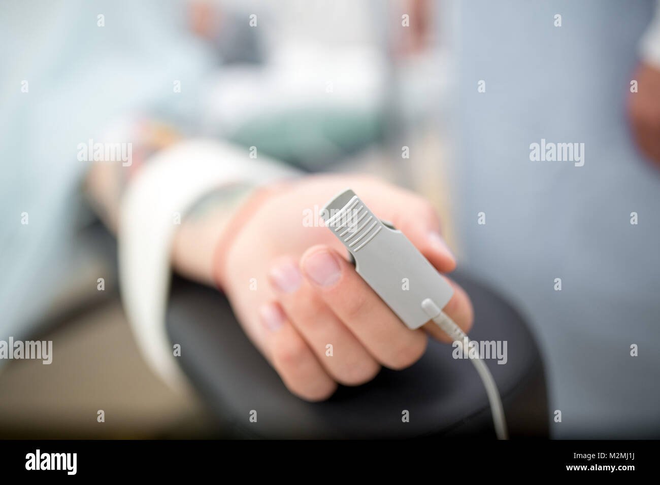 pulse oximeter on finger of patient during surgery. male patient lying ...