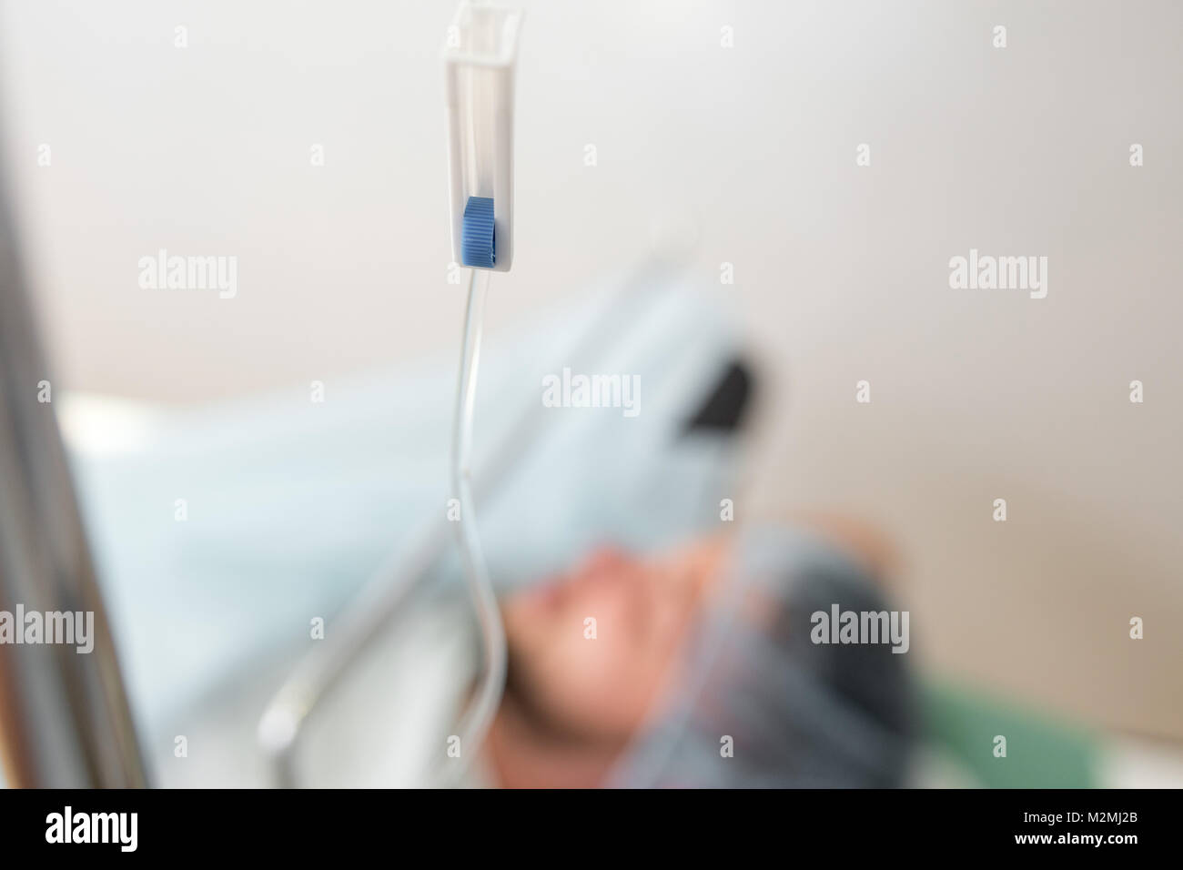 Set iv fluid intravenous drop saline drip in foreground, patient on the ...