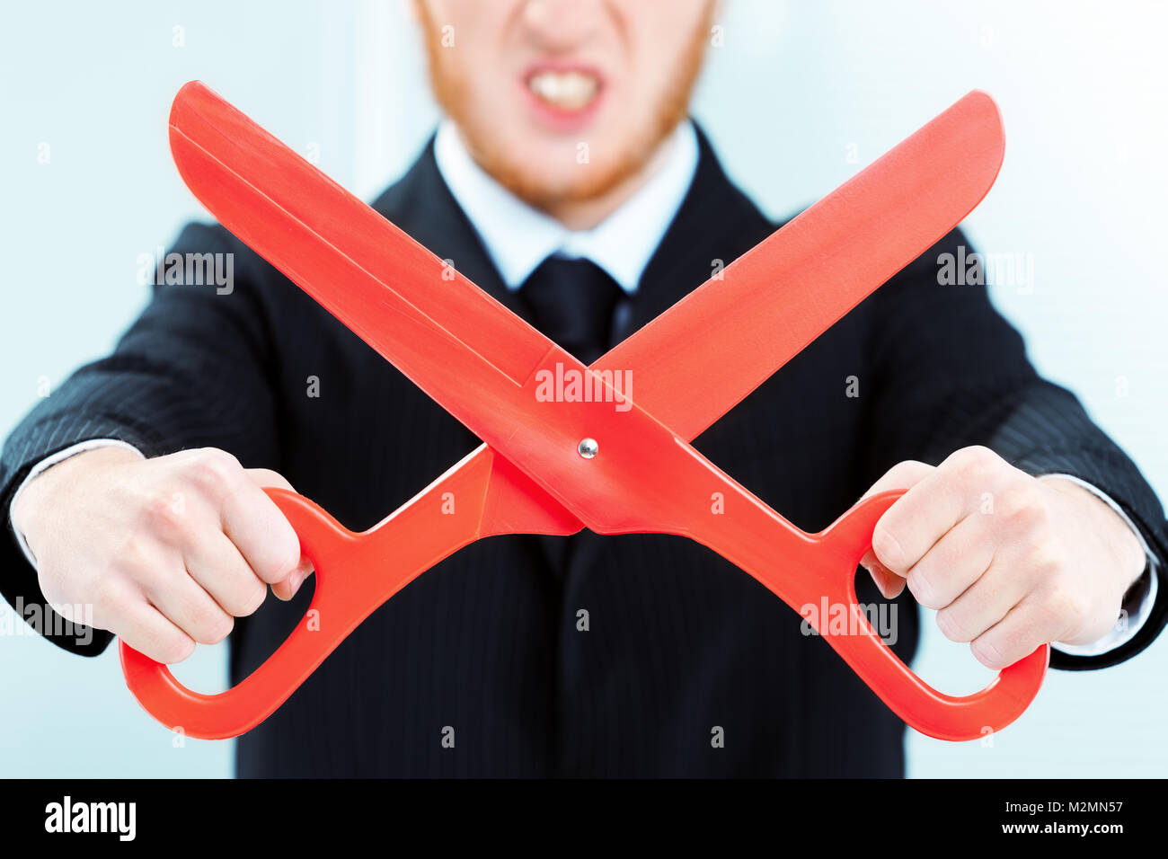 Man with harsh face wearing suit holding big red open scissors Stock ...